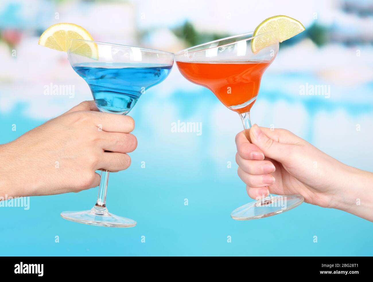Cocktails in men's and women's hands on pool background Stock Photo - Alamy