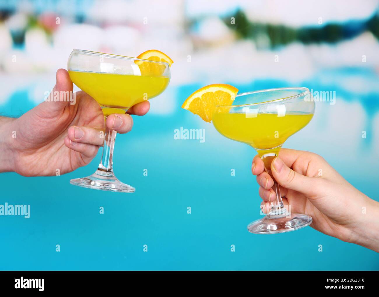 Cocktails in men's and women's hands on pool background Stock Photo - Alamy