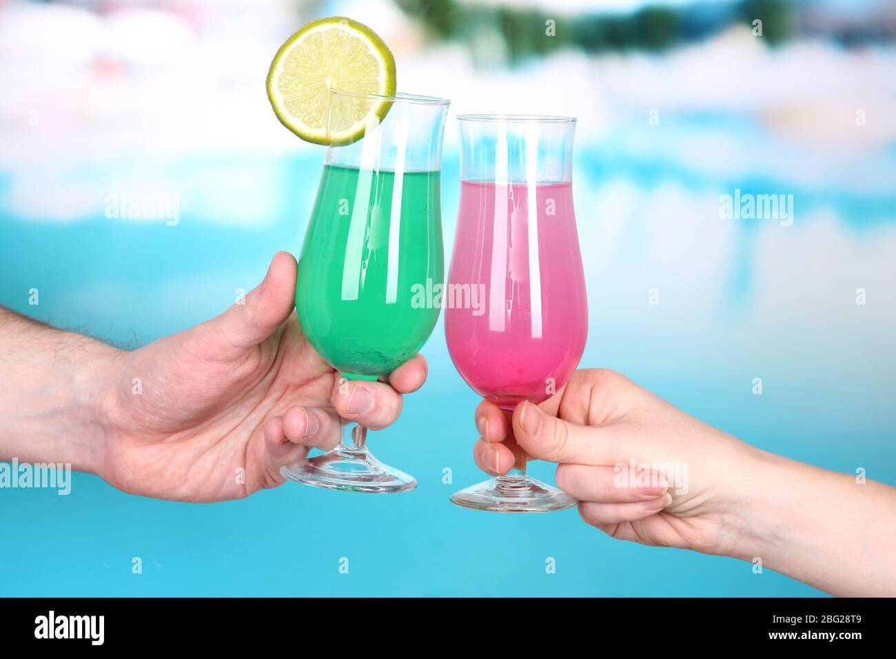 Cocktails in men's and women's hands on pool background Stock Photo - Alamy
