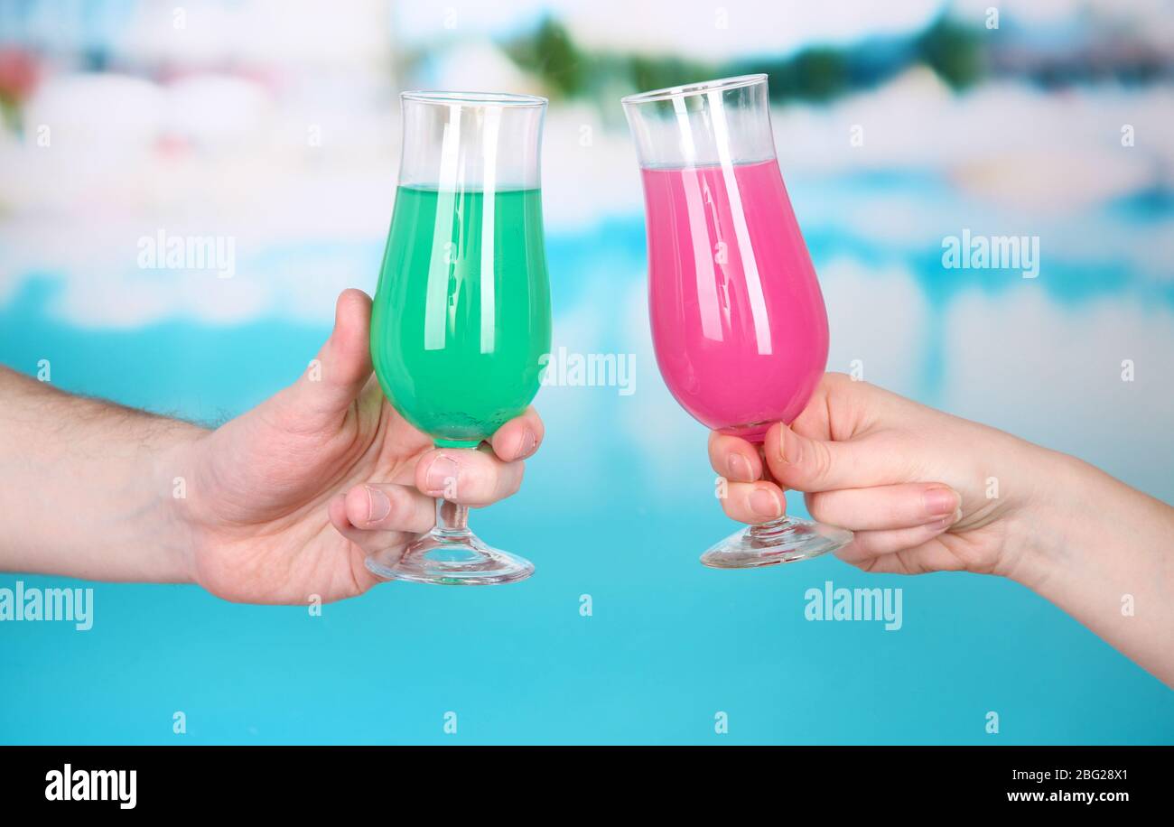 Cocktails in men's and women's hands on pool background Stock Photo - Alamy