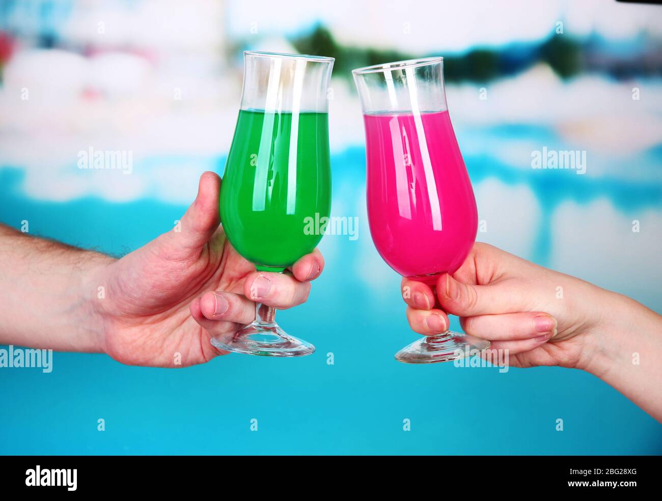 Cocktails in men's and women's hands on pool background Stock Photo - Alamy