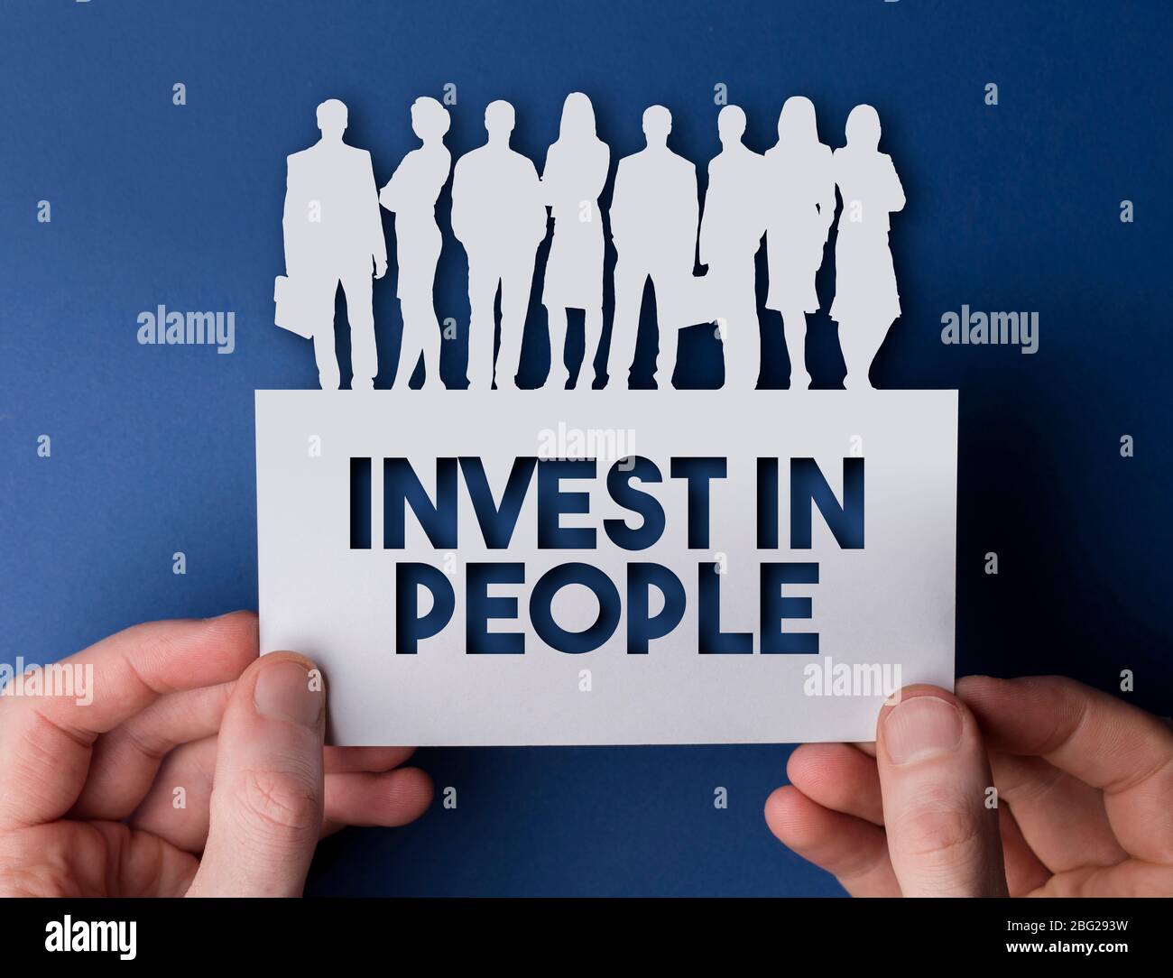 Hands holding an invest in people white card business team people sign ...
