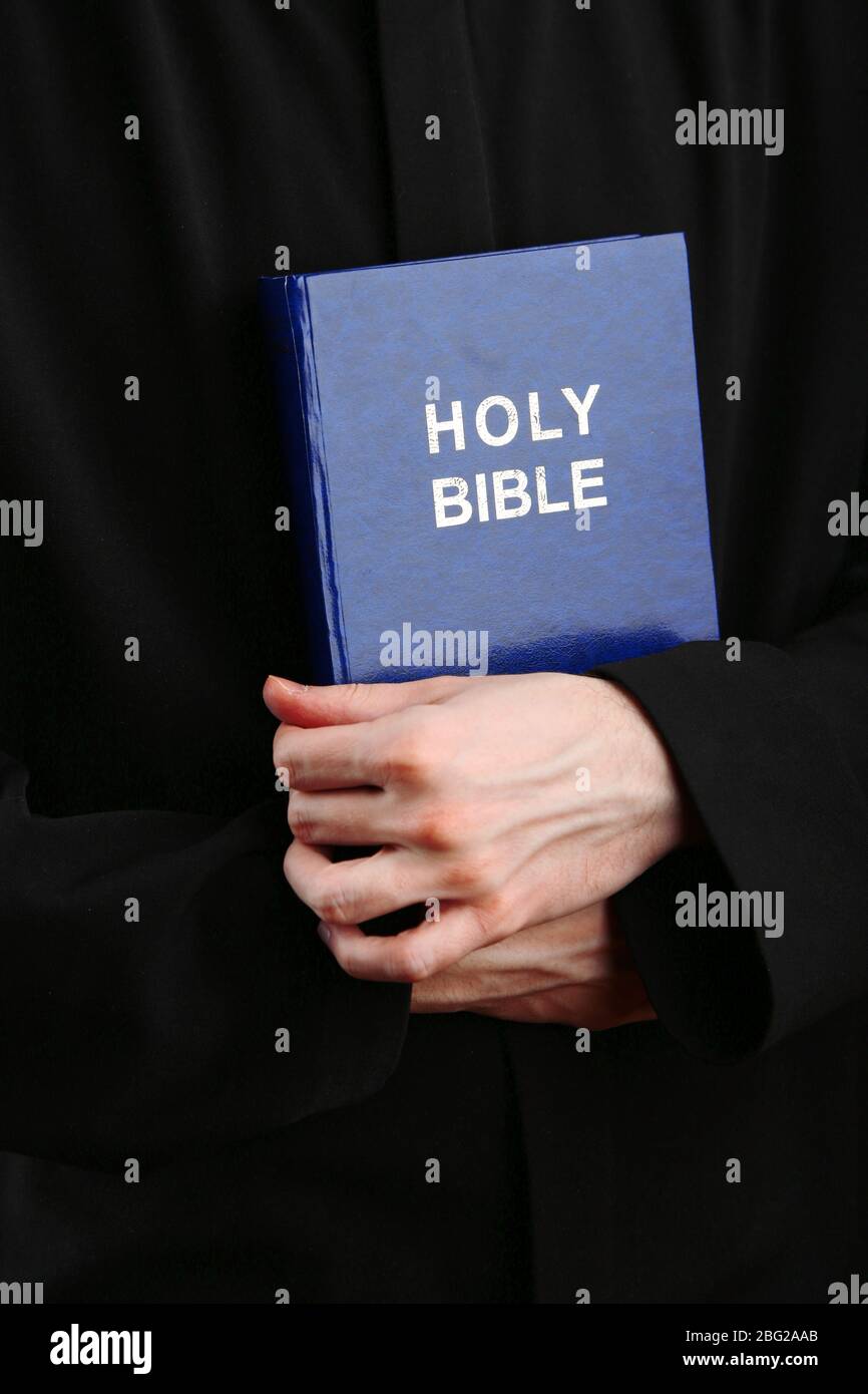 Priest holding holy bible, close up Stock Photo - Alamy