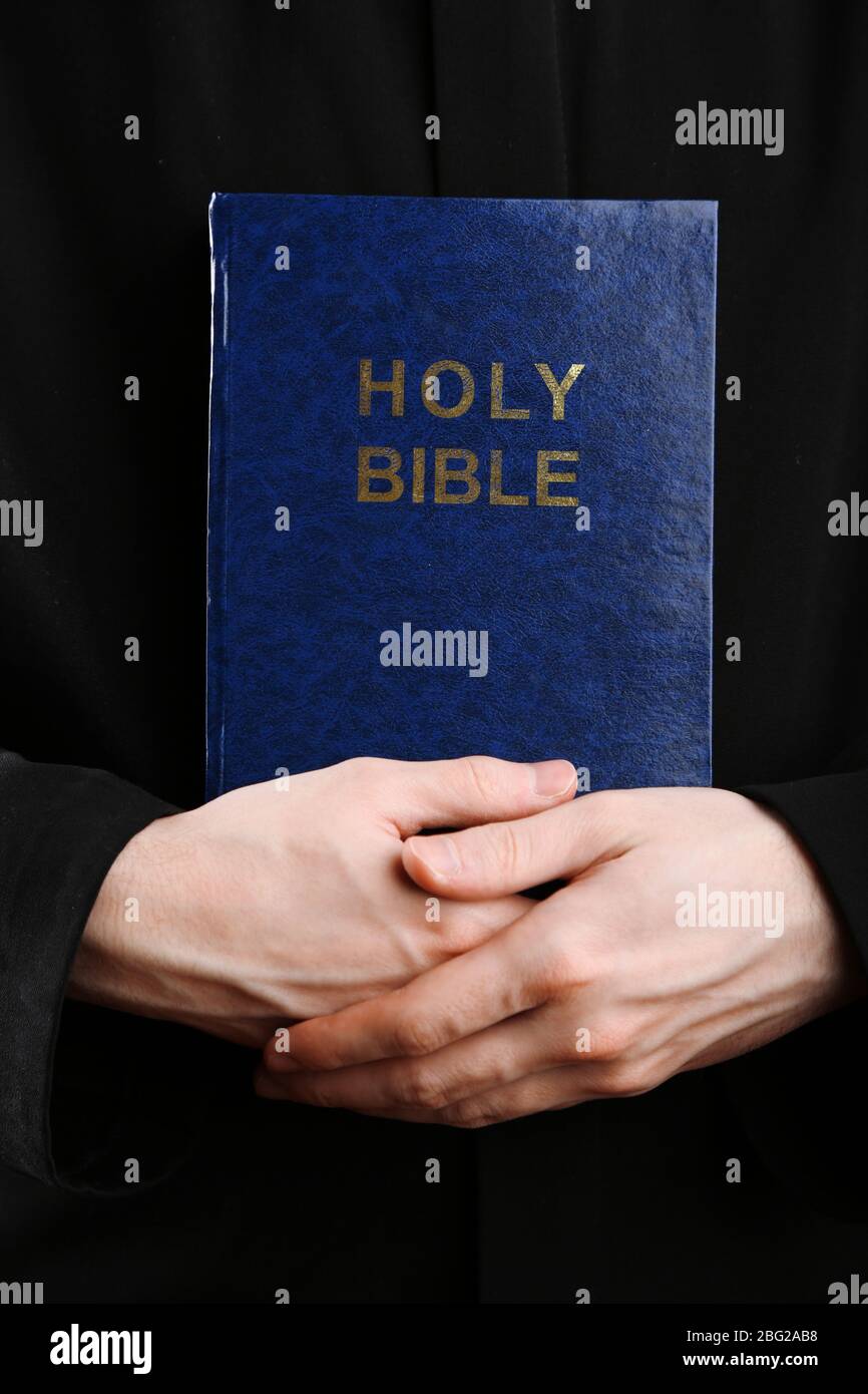 Priest holding holy bible, close up Stock Photo - Alamy