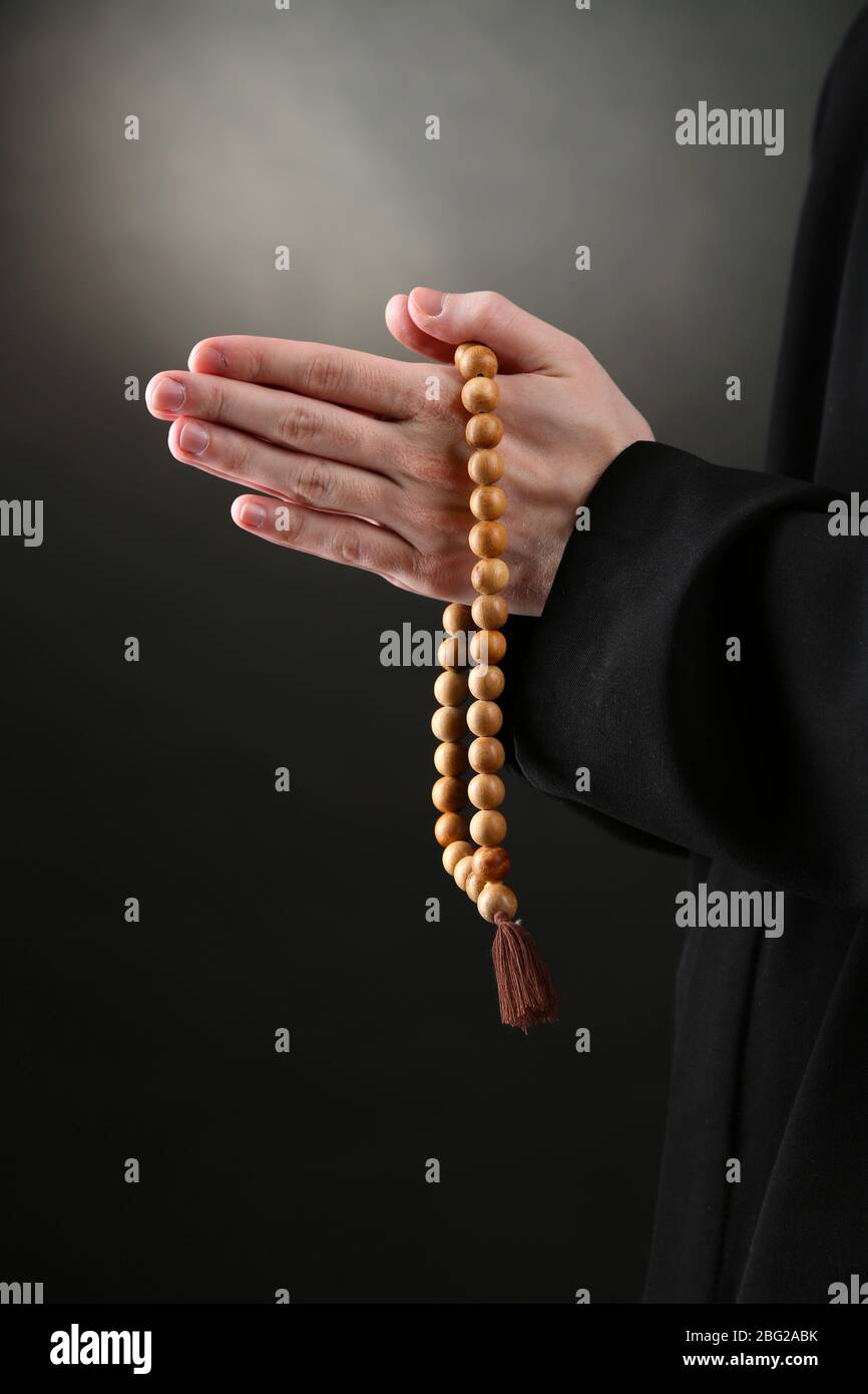 Priest holding rosary, on black background Stock Photo - Alamy