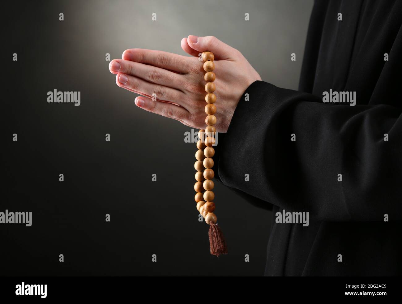 Priest holding rosary, on black background Stock Photo - Alamy