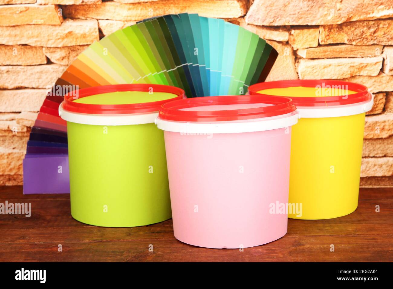 Paint pots, palette of colors on wooden table on stone wall background ...