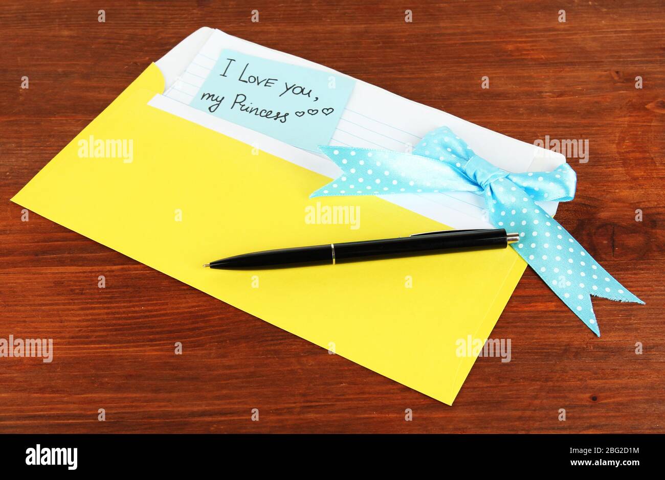 Note in envelope with pen on wooden background Stock Photo - Alamy