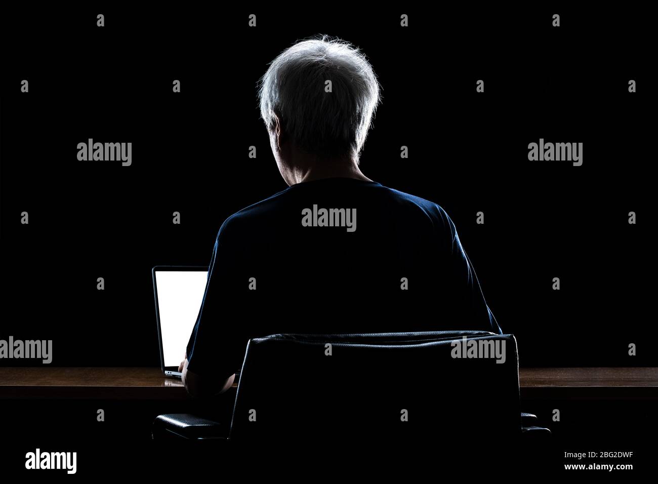 Back view of a man with gray hair working from home late at night using ...