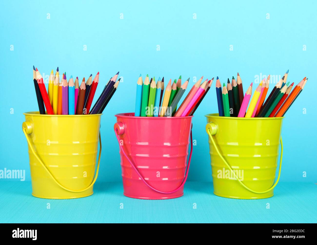 Colorful pencils in three pails on blue background Stock Photo - Alamy