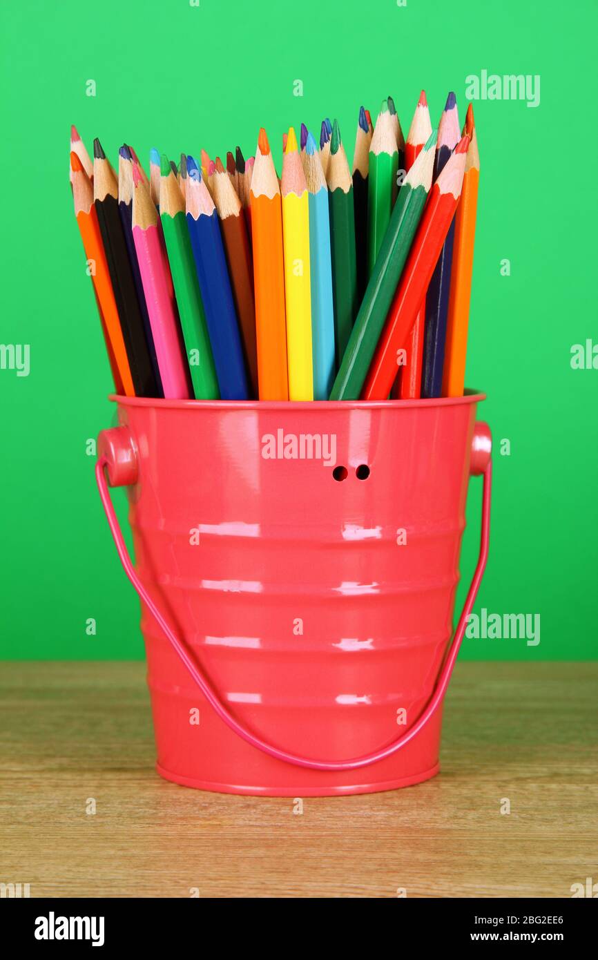 Colorful pencils in pail on table on green background Stock Photo - Alamy