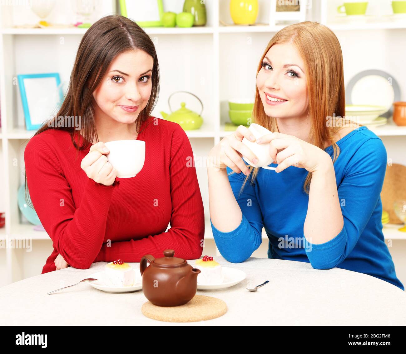Two girl friends talk and drink tea in kitchen Stock Photo - Alamy
