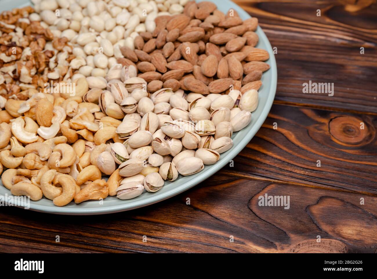Assortment of nuts on a plate. Wooden board. Healthy snack. Flat lay ...