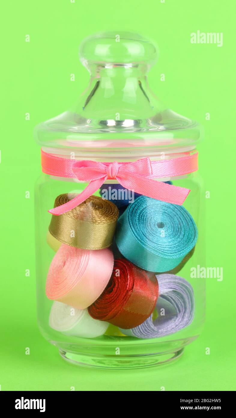 Glass jar containing various colored ribbons on green background Stock ...