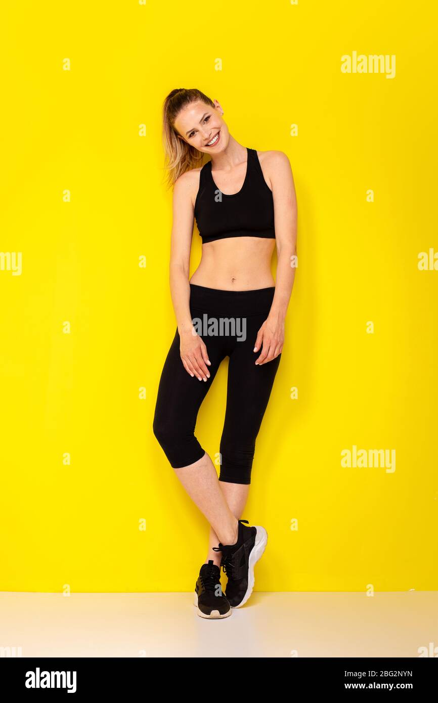 nice and slim fit woman resting on a yellow background in fitness ...