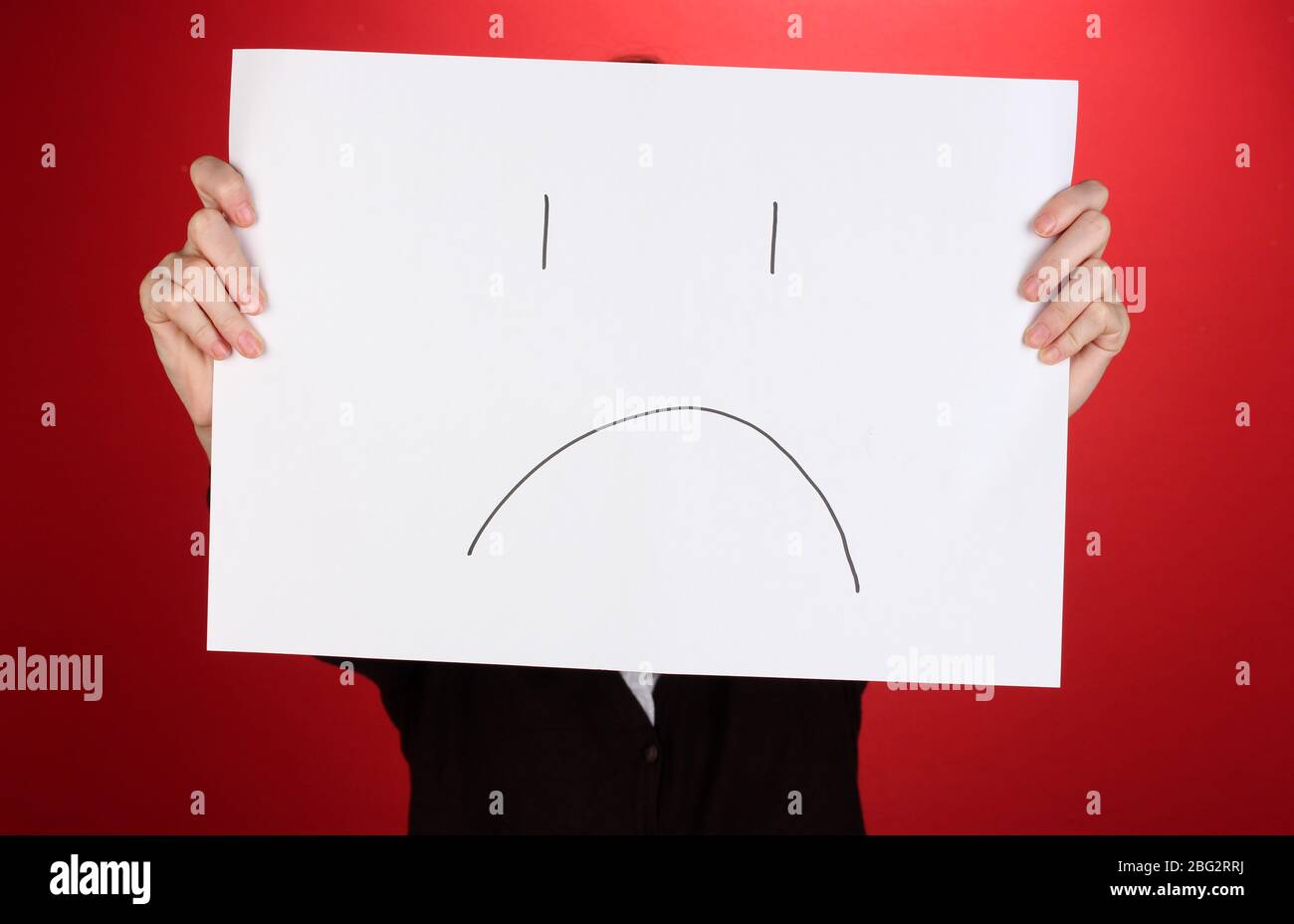 Woman holding paper with sad emoticon, on color background Stock Photo ...