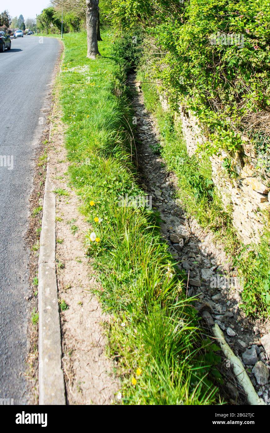 A dry and empty roadside drainage channel which fills with water when ...