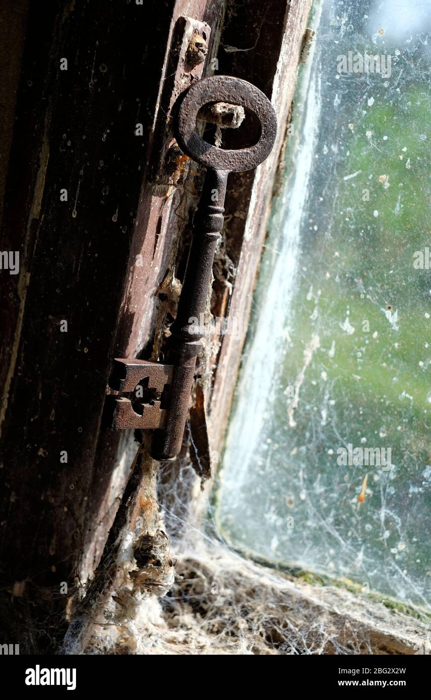 old rusty key hanging in dirty window with cobwebs Stock Photo - Alamy