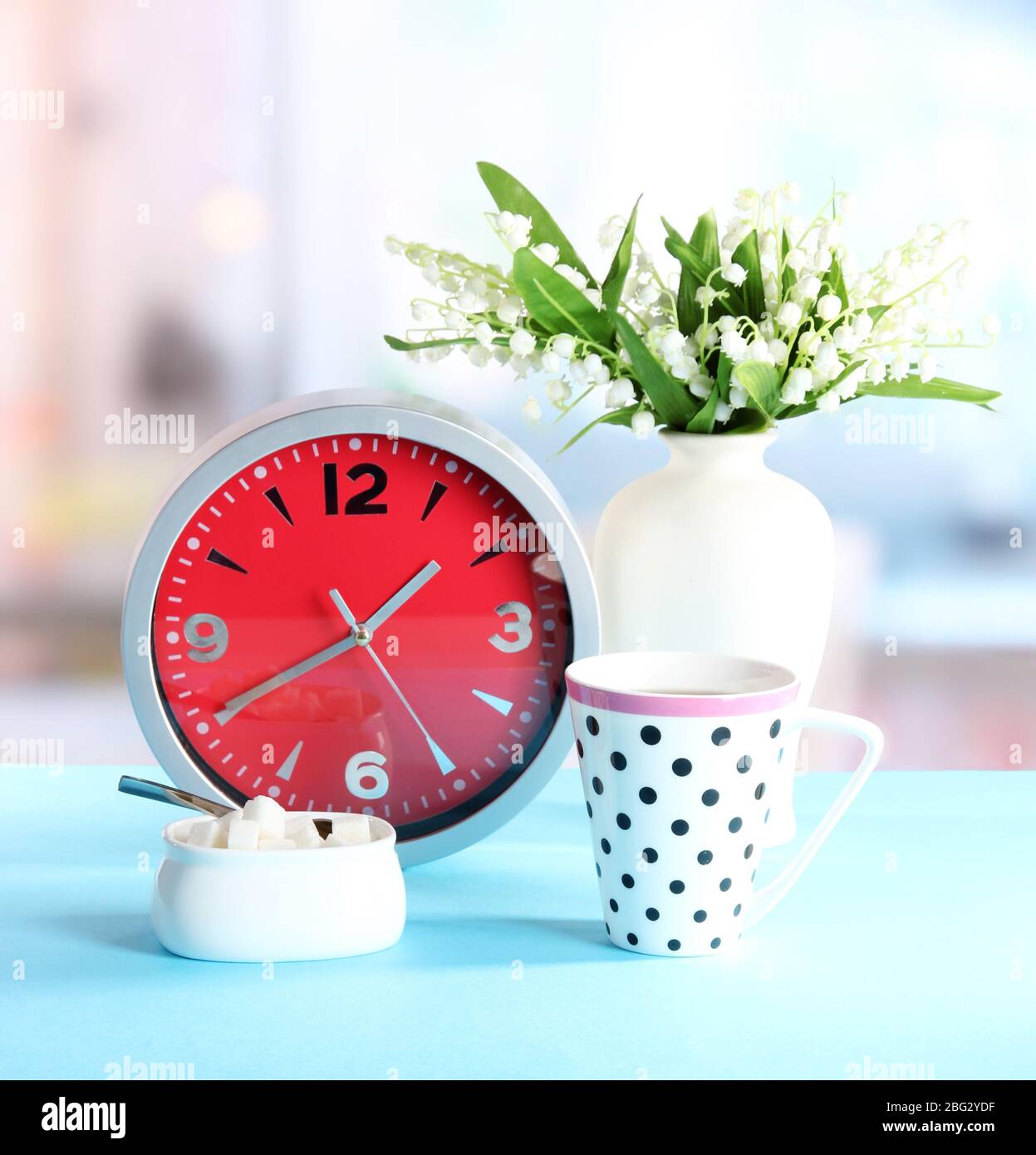 Cup tea and clock on bright background Stock Photo - Alamy