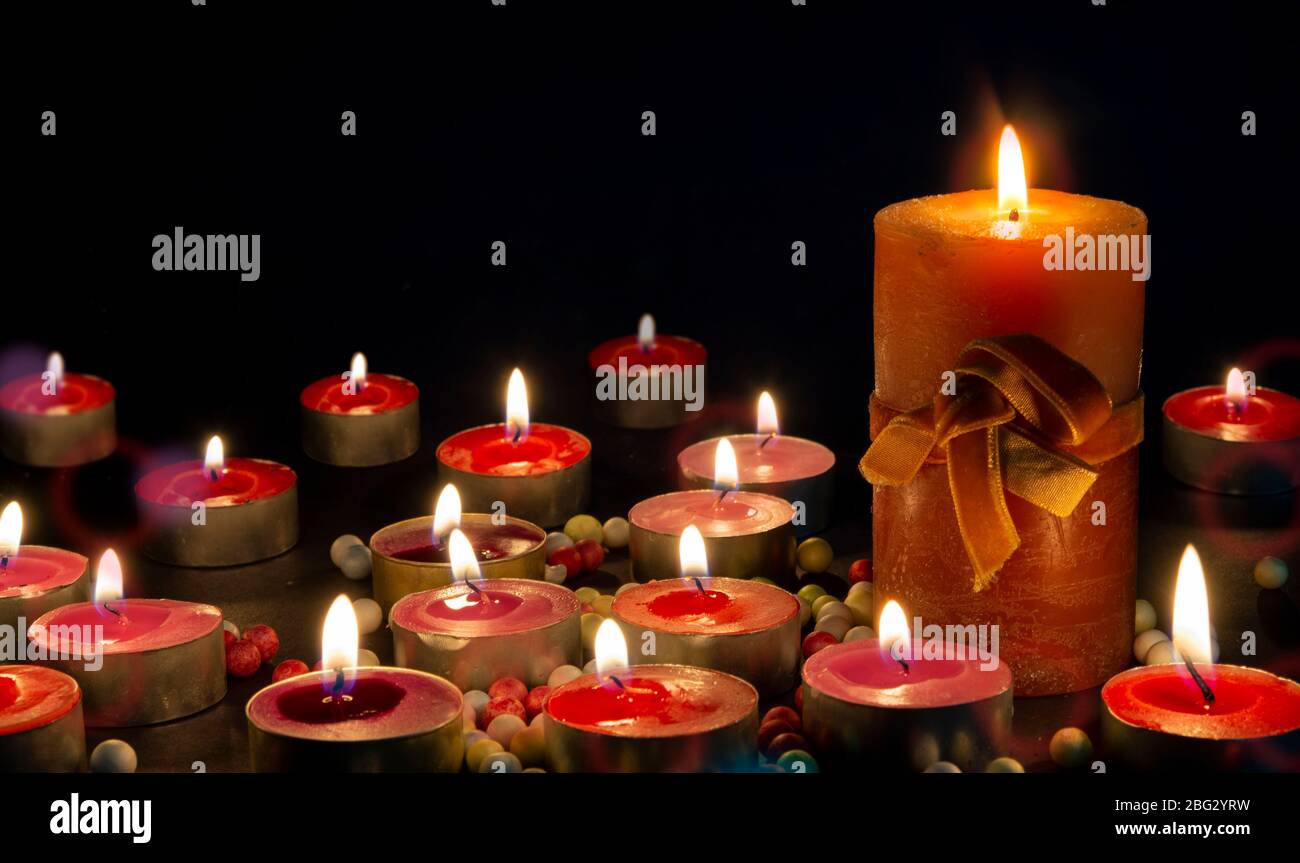 Burning golden candles on black background. grief, mourning or ...
