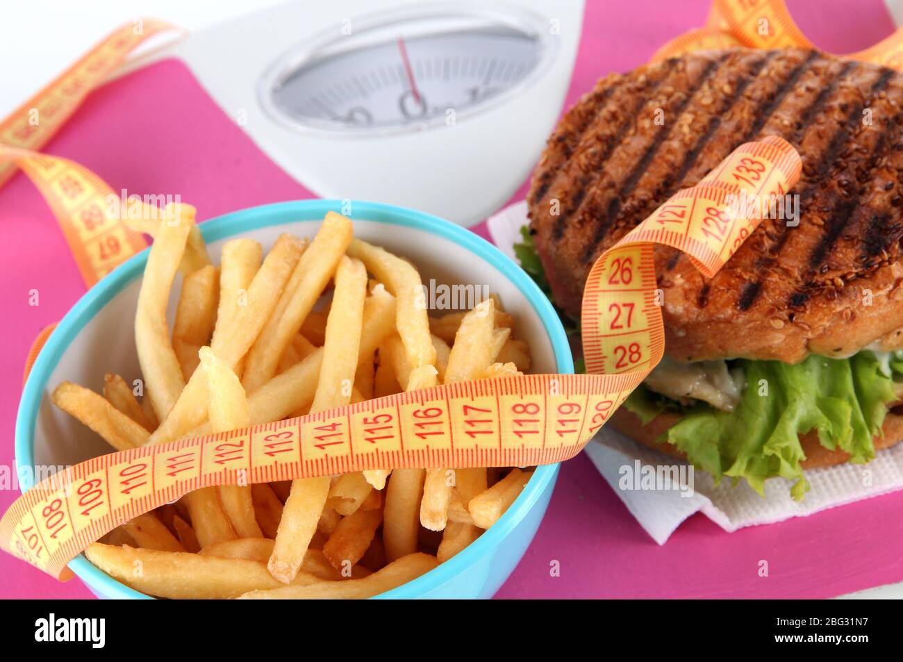 Hot-dog, hamburger and fries on scales close-up Stock Photo - Alamy