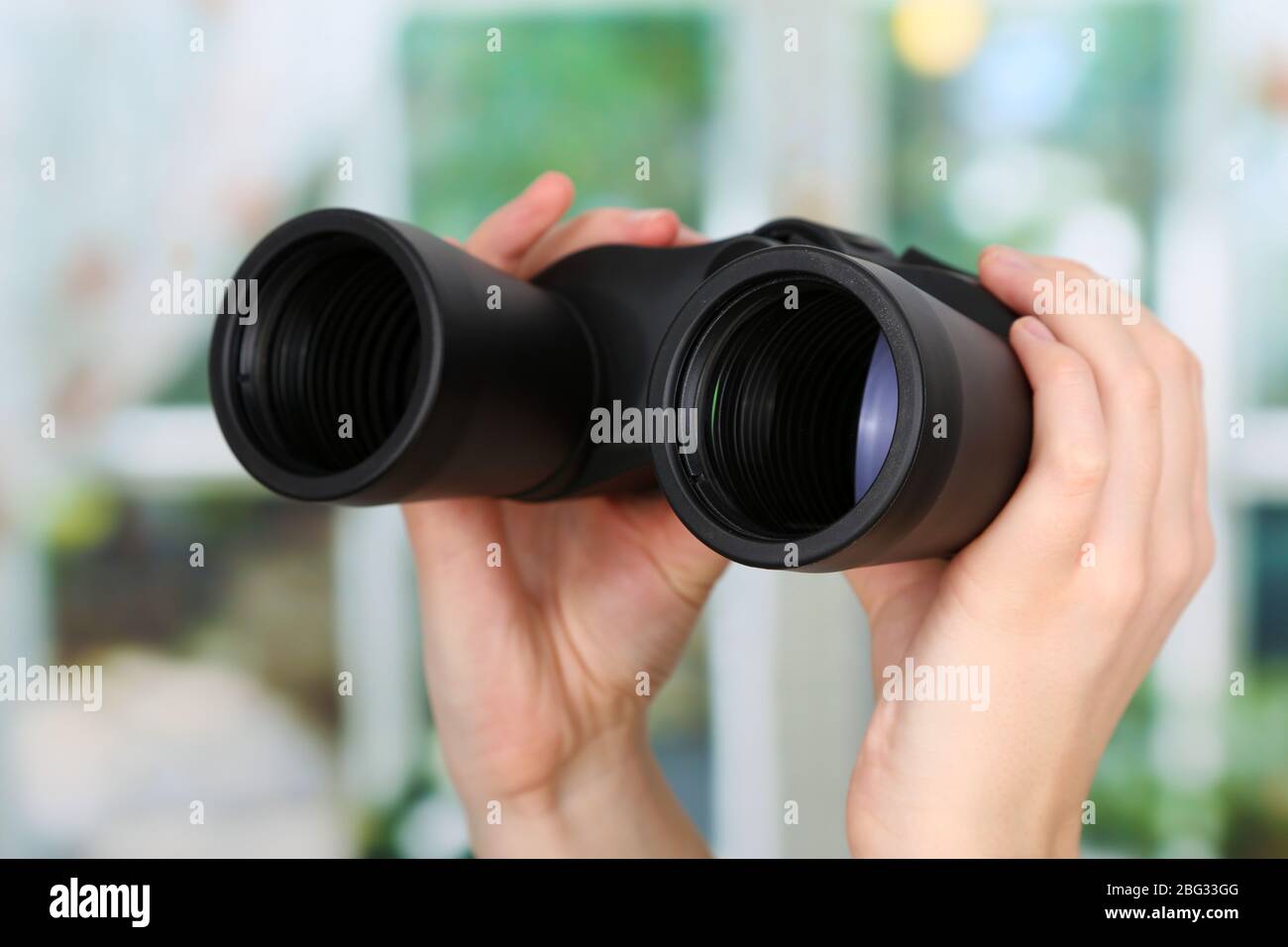 Black modern binoculars in hands on window background Stock Photo - Alamy