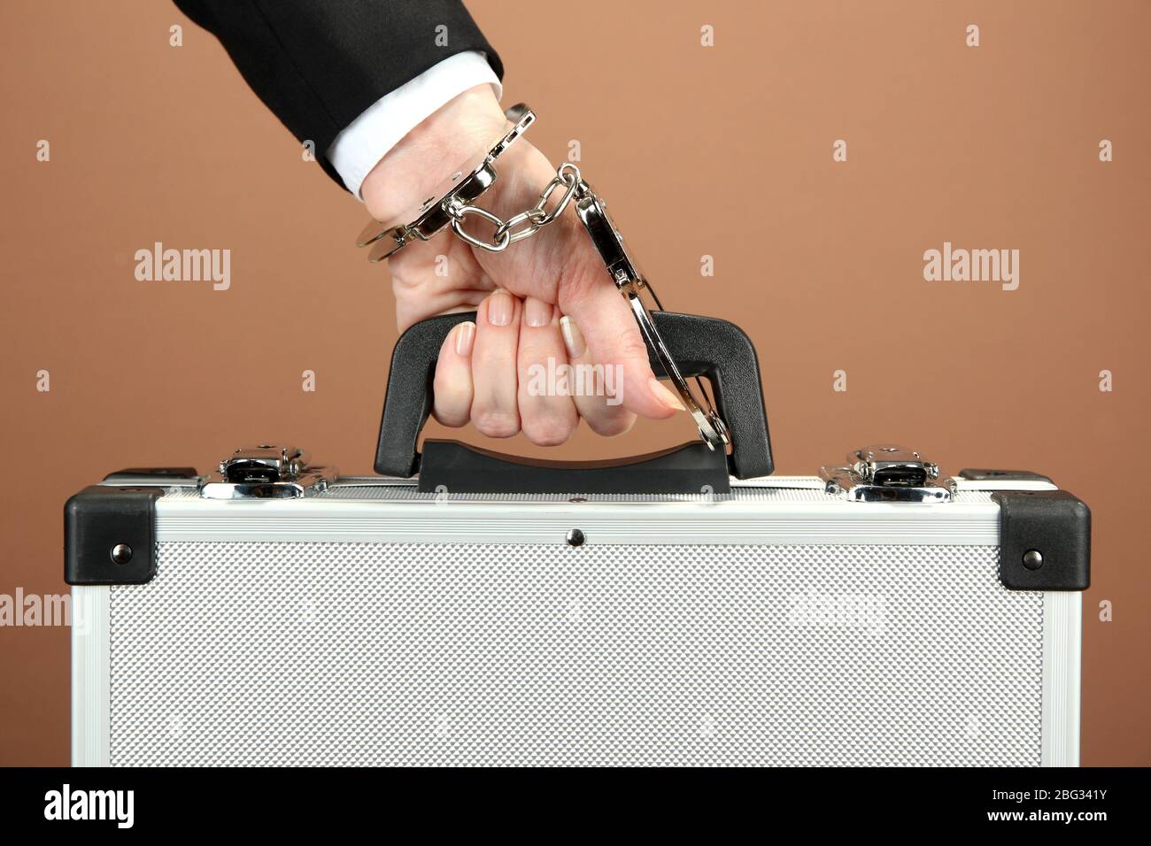 Hand with handcuff and suitcase, on color background Stock Photo - Alamy