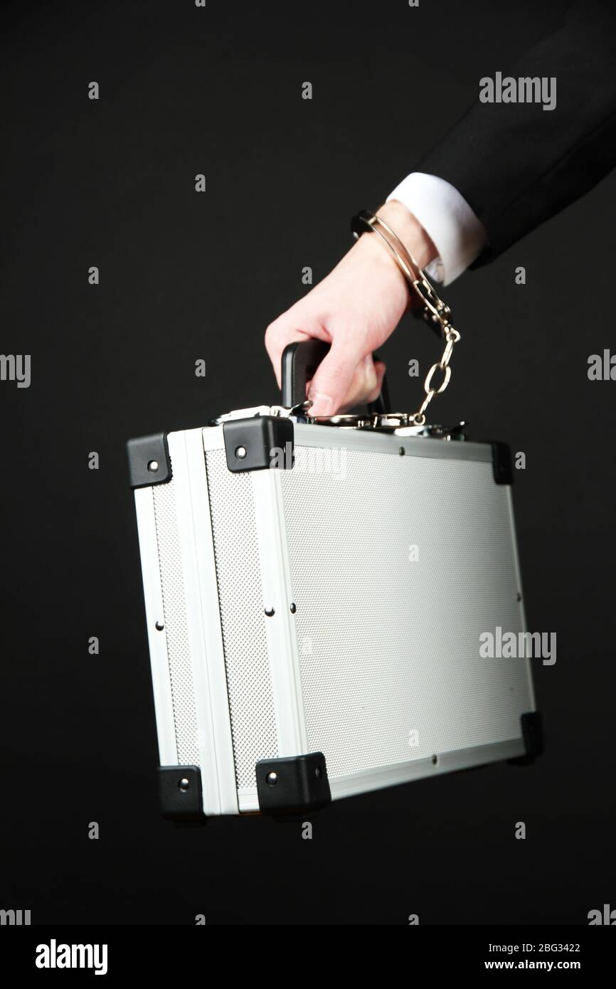 Hand with handcuff and suitcase, isolated on black Stock Photo - Alamy