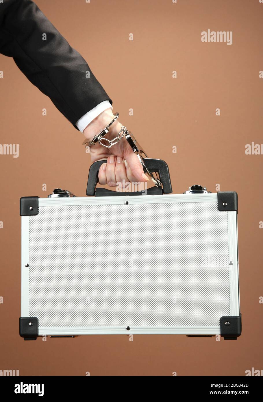 Hand with handcuff and suitcase, on color background Stock Photo - Alamy