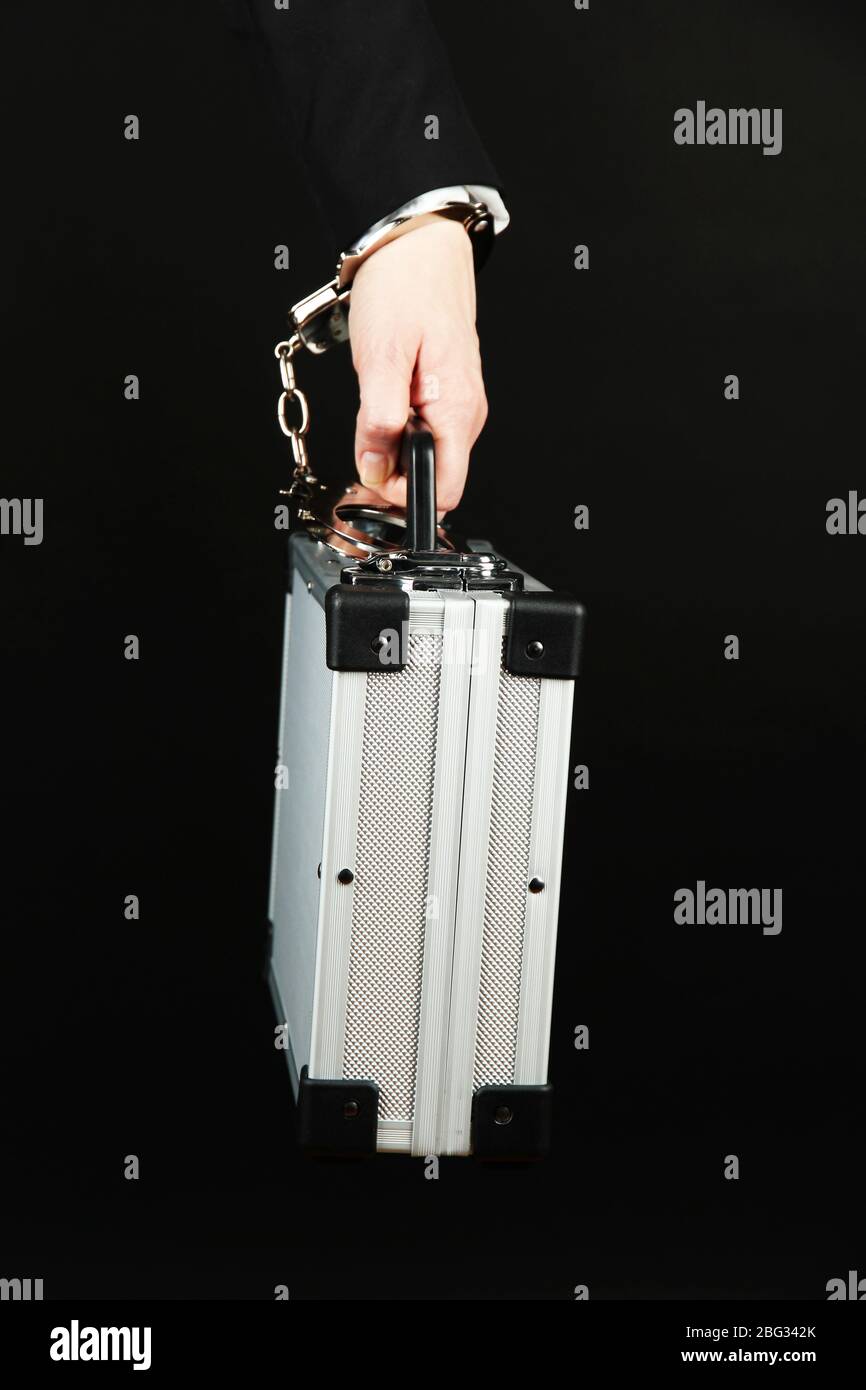 Hand with handcuff and suitcase, isolated on black Stock Photo - Alamy