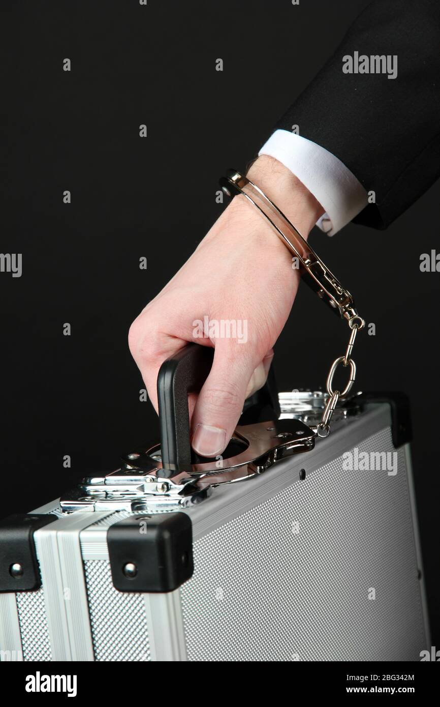 Hand with handcuff and suitcase, isolated on black Stock Photo - Alamy