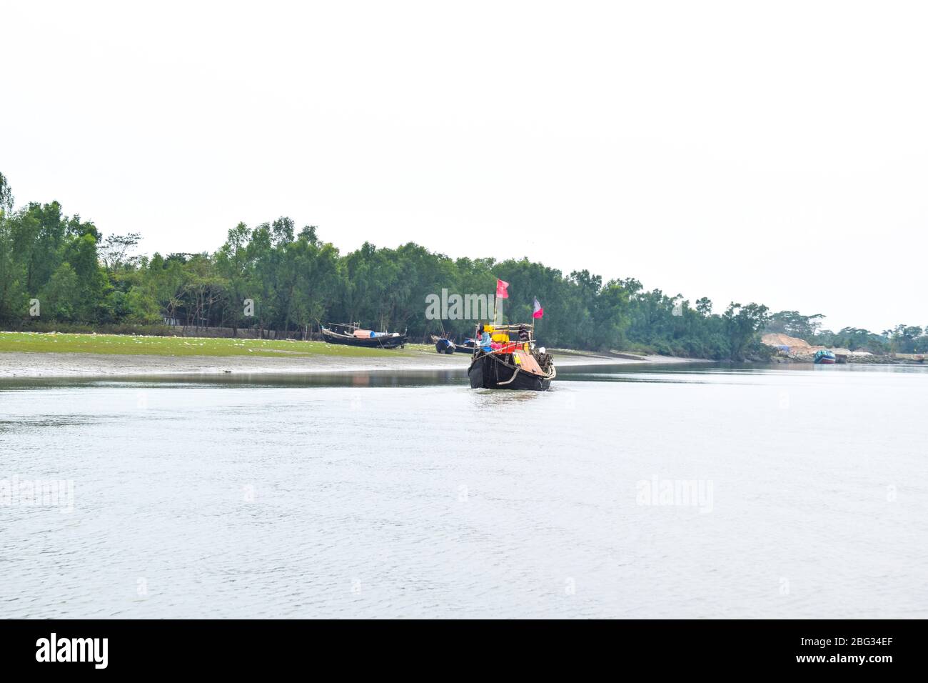Small sized fishing boat ported on a small bank of a river side while ...