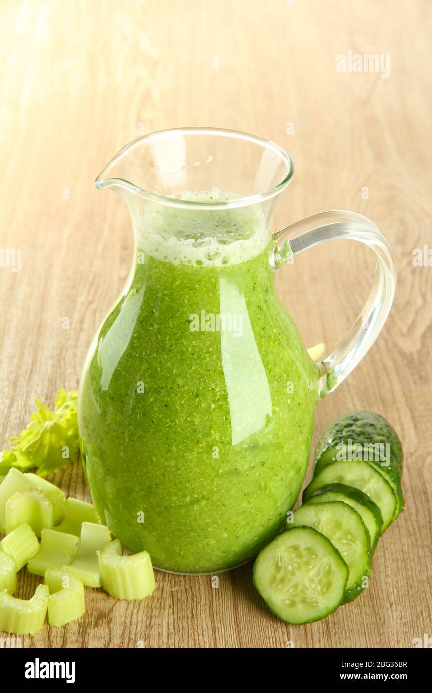 Glass pitcher of green vegetable juice on wooden background Stock Photo ...