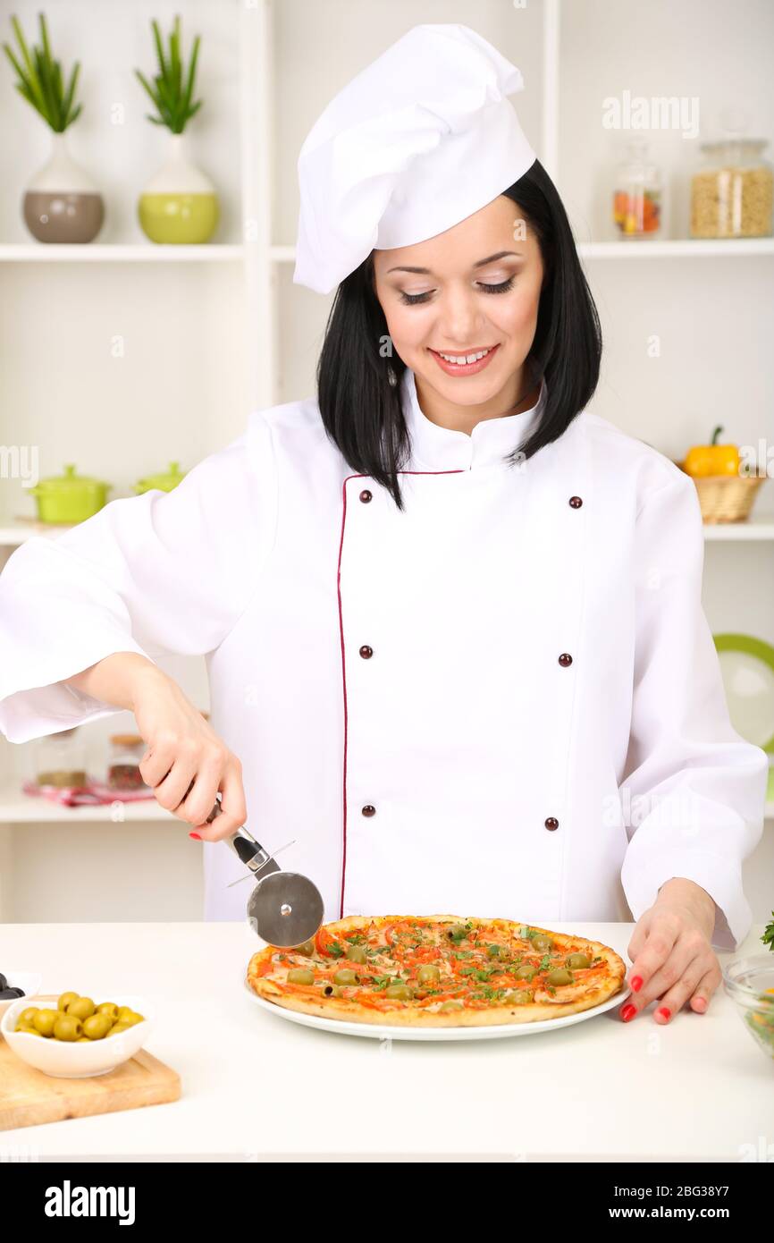 Beautiful girl chief-cooker with pizza on kitchen background Stock ...