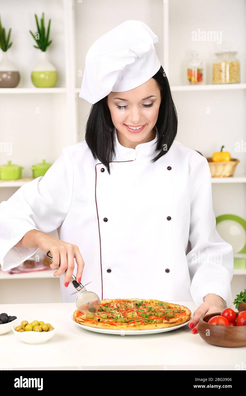 Beautiful girl chief-cooker with pizza on kitchen background Stock ...