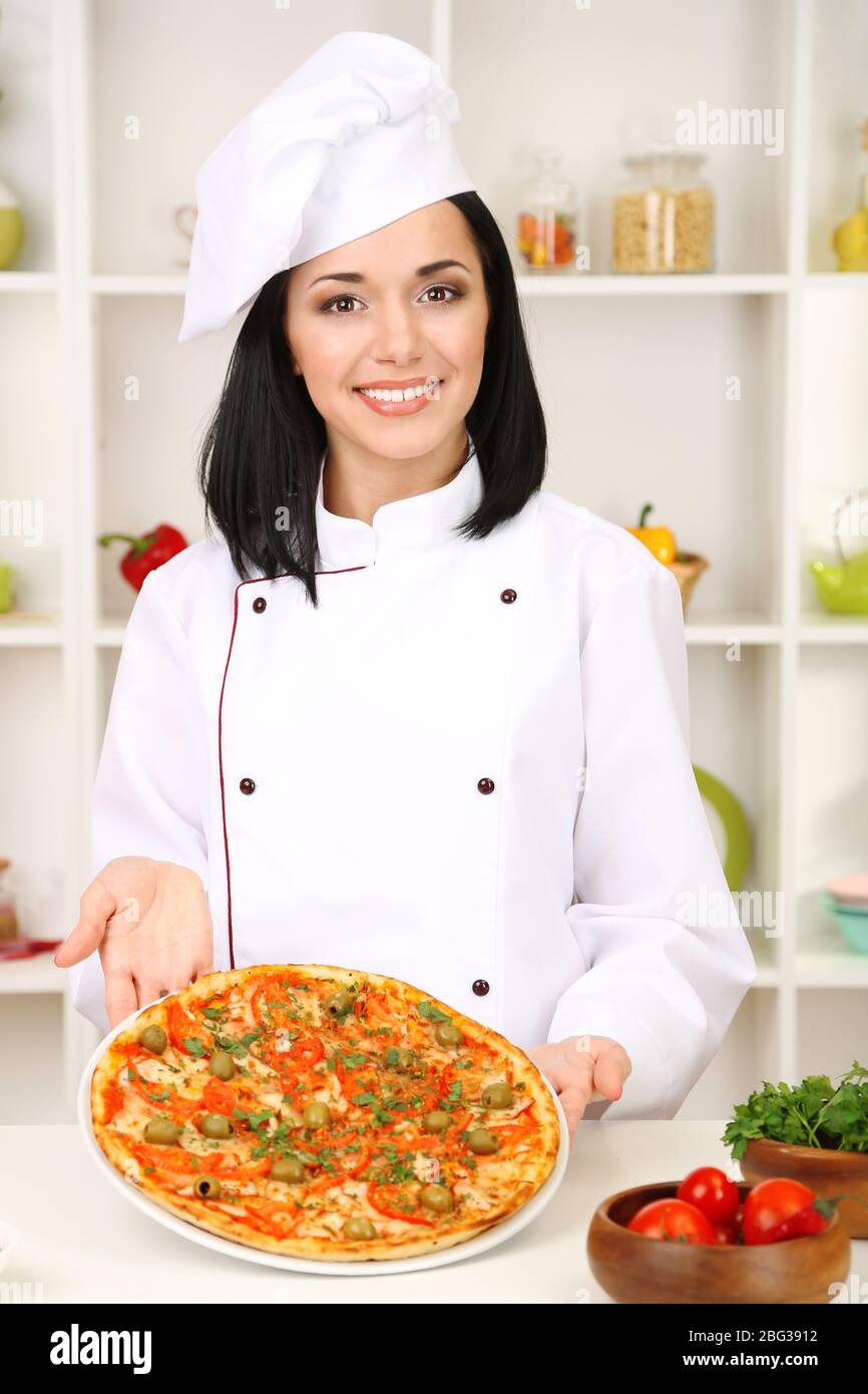 Beautiful girl chief-cooker with pizza on kitchen background Stock ...