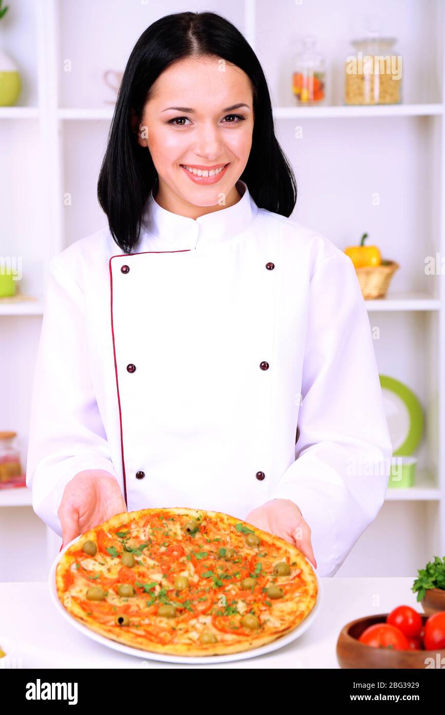 Beautiful girl chief-cooker with pizza on kitchen background Stock ...
