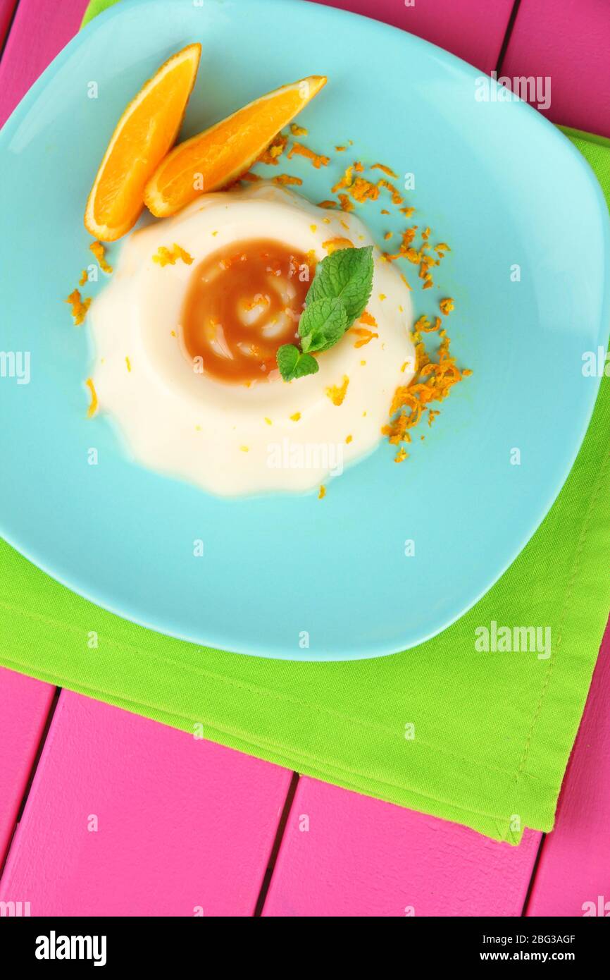 Panna Cotta with orange zest and caramel sauce, on color wooden ...