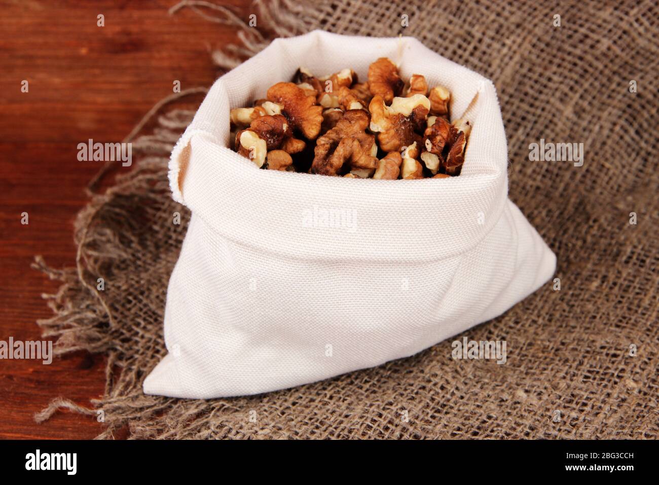 Nuts in sack on wooden background Stock Photo - Alamy