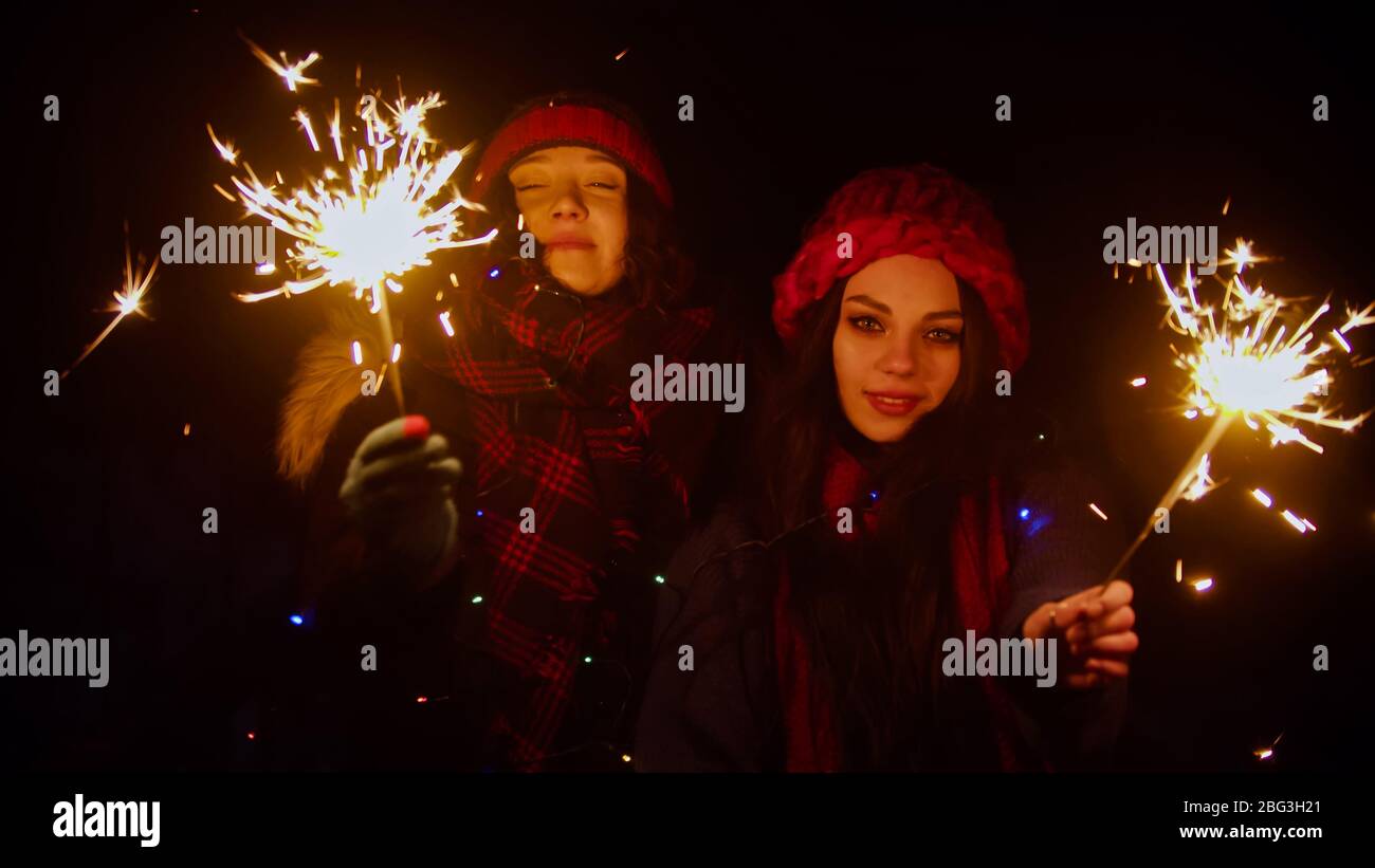 Two young women holding sparklers at night - mid shot Stock Photo - Alamy