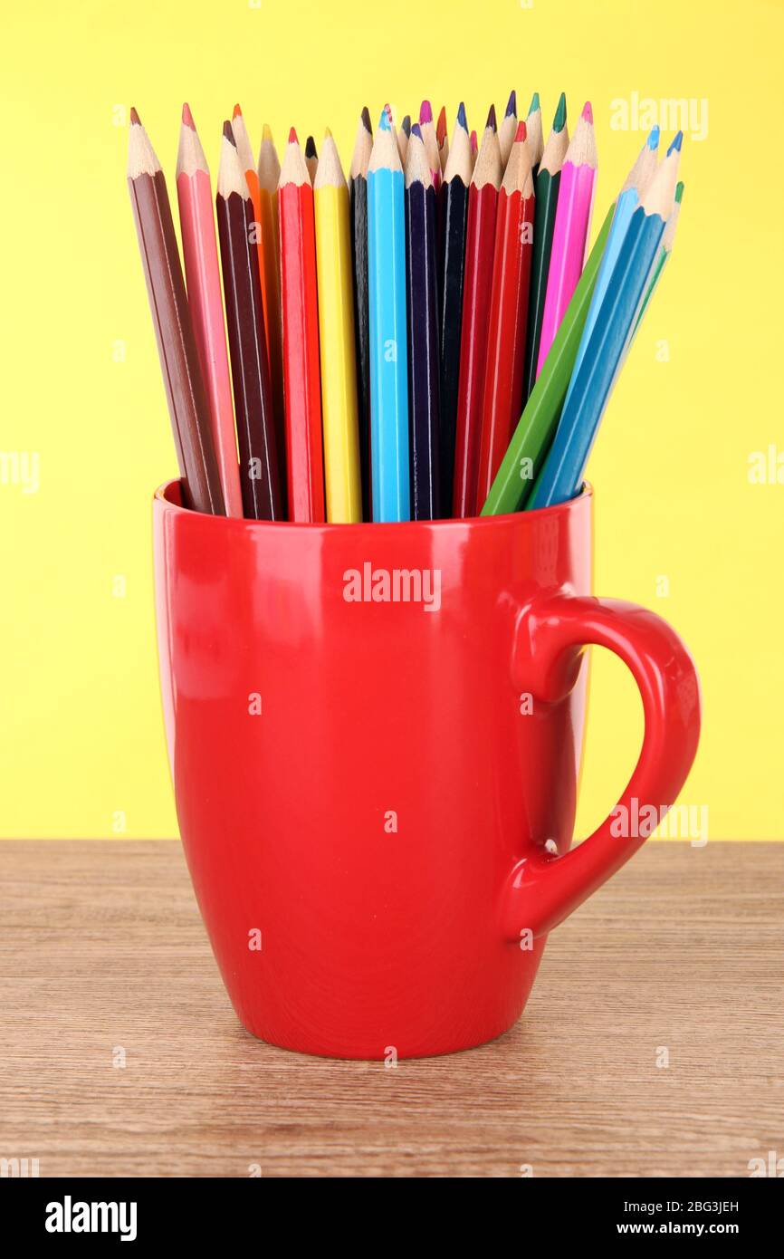 Colorful pencils in cup on table on yellow background Stock Photo - Alamy