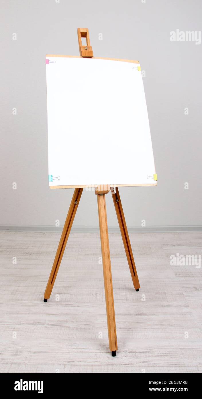 Wooden easel with clean paper in room Stock Photo - Alamy
