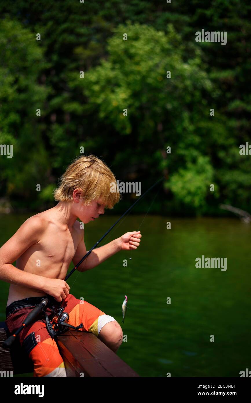 A young boy fishing on a dock in the summer, USA Stock Photo - Alamy