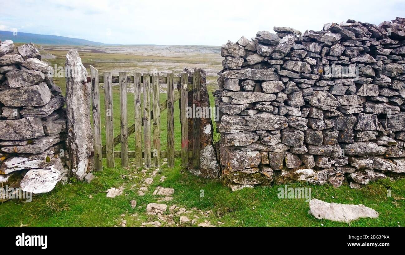 A public footpath gate between two walls of limestone separates 2 ...