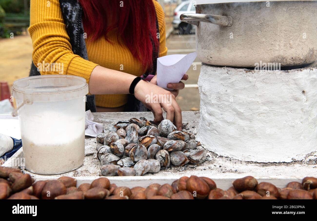 Woman picking roasted chestnuts at a street stall, Seville, Spain Stock ...