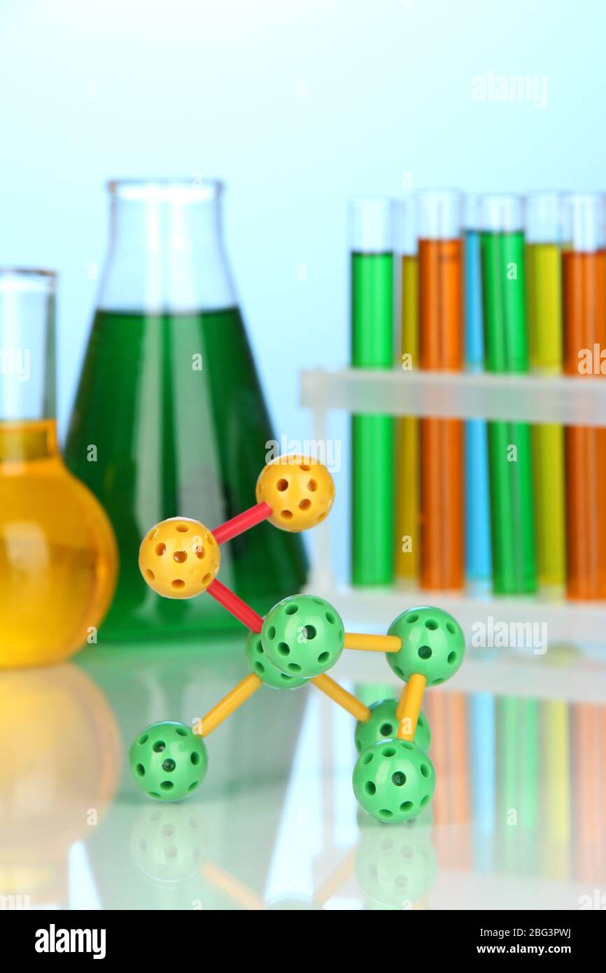 Molecule model and test tubes with colorful liquids on blue background ...
