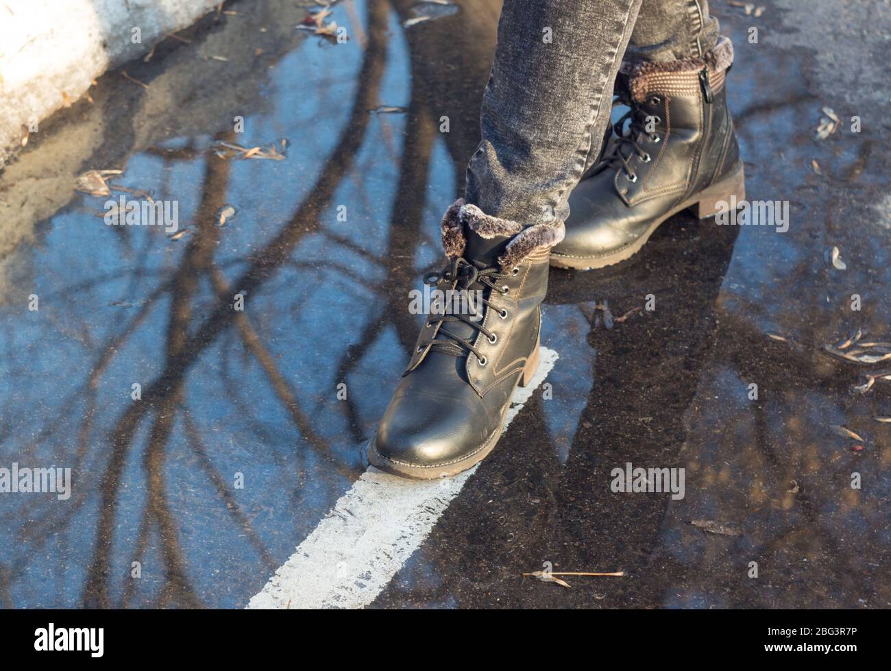 Women's feet in a puddle. Shoes, boots, go, walk. Asphalt, markings ...