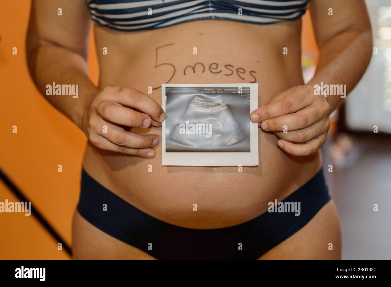Beautiful Five month pregnant woman showing her ultrasound in her hands next to the belly. June ...