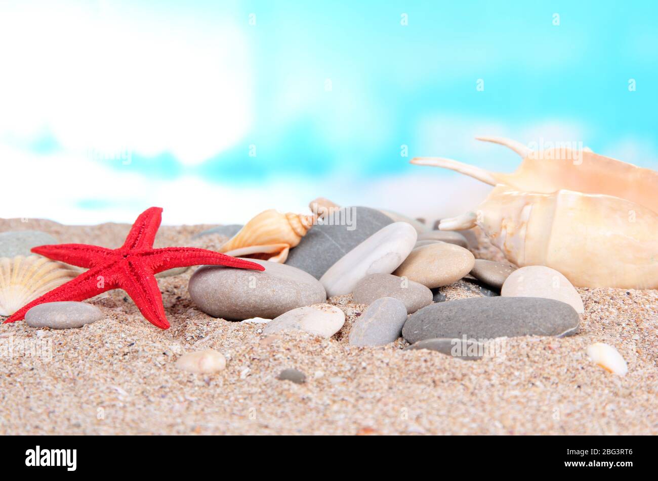 Sea stones on sand on bright background Stock Photo - Alamy