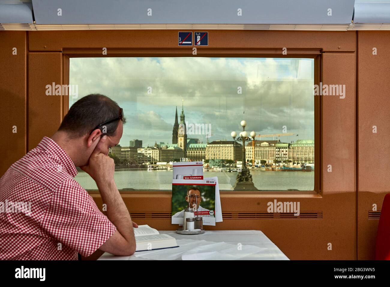 A passenger reading a book in the restaurant car of a train crossing ...